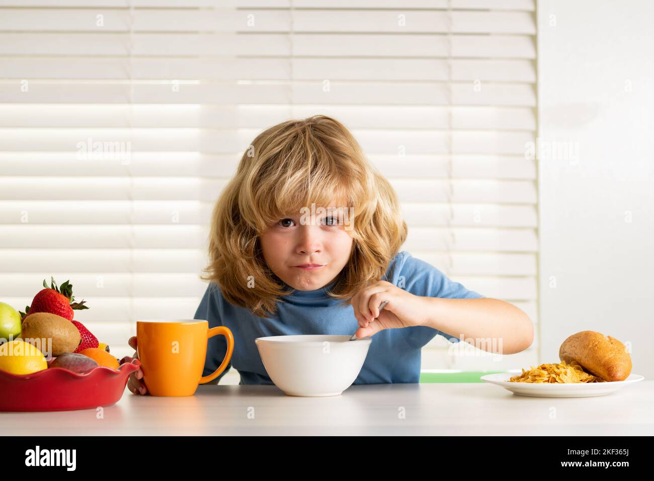 Kid preteen boy in the kitchen at the table eating vegetable and fruits ...