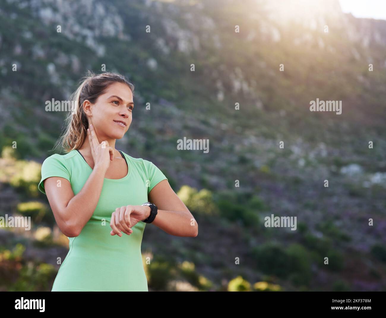 Not too bad. a young woman checking her heart rate while exercising ...