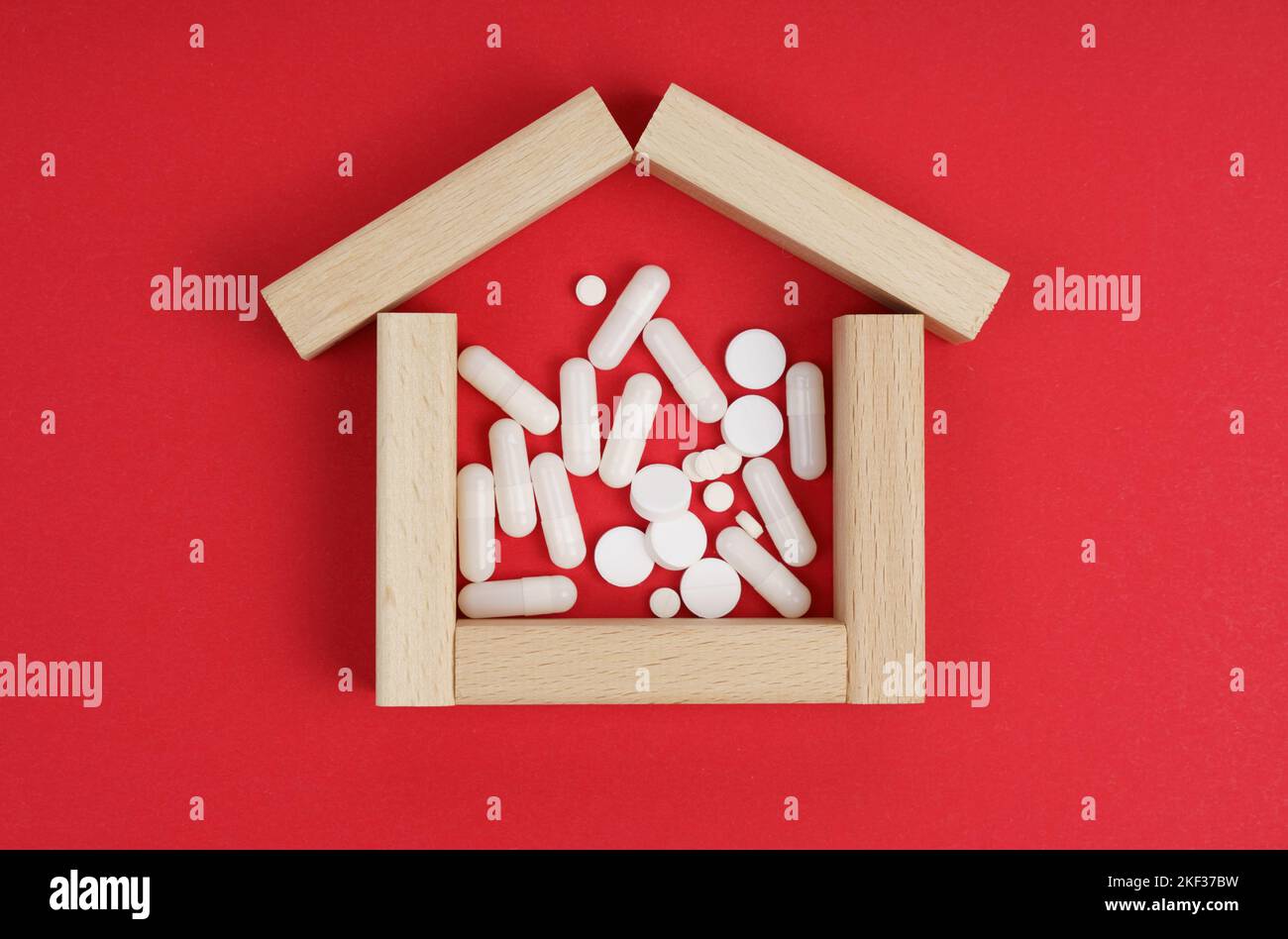 Medical concept. On a red background, a small house made of wooden ...