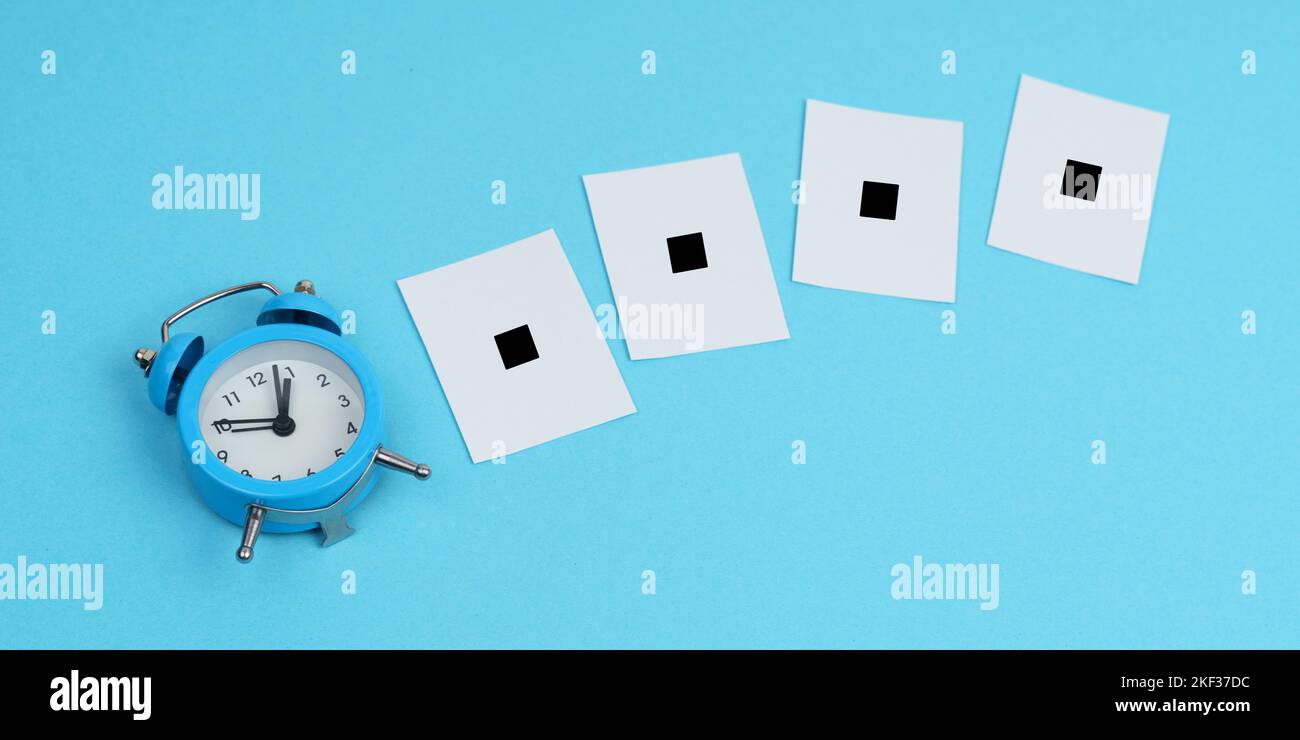 On a blue background, an alarm clock and white pieces of paper with a ...