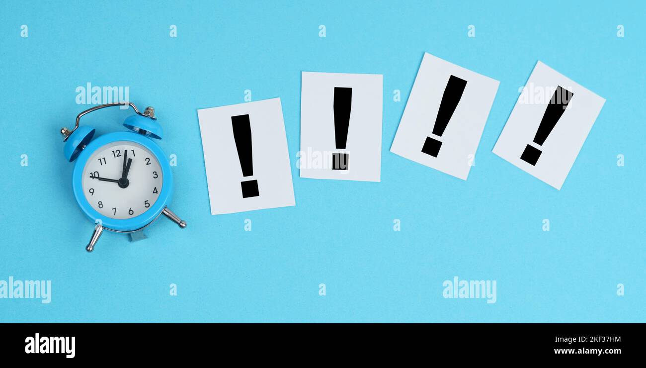 On a blue background, an alarm clock and white pieces of paper with an ...