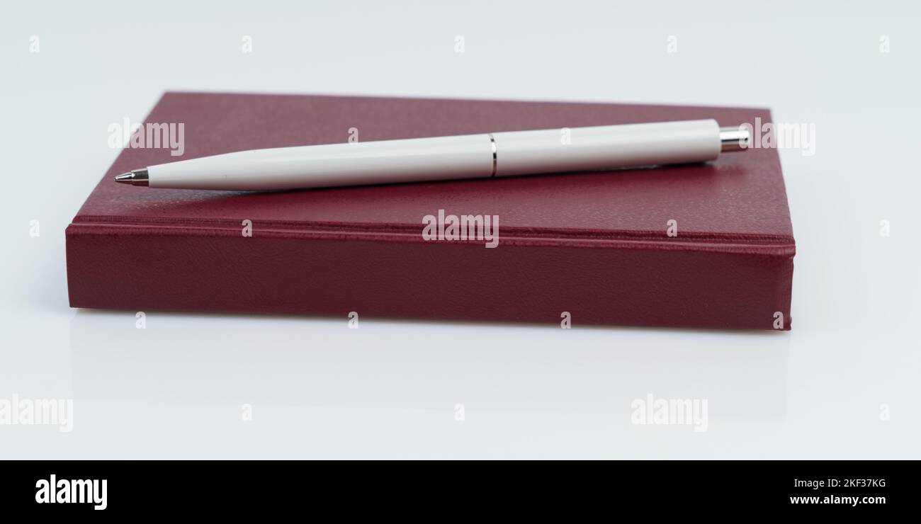 Education concept. On a white background, a red notepad and a white pen ...