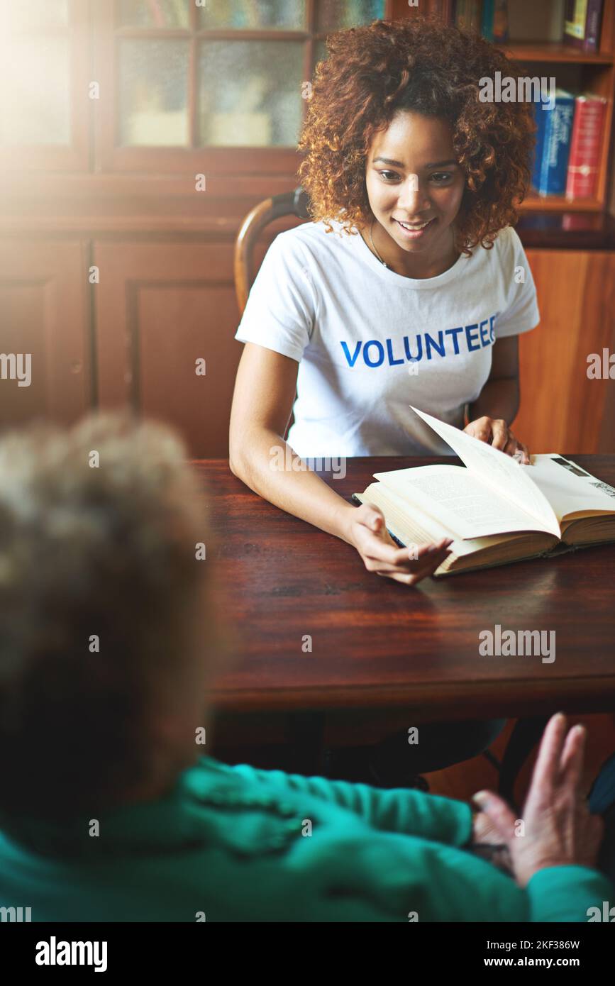 Sharing her love for reading. a volunteer reading to a senior woman at ...
