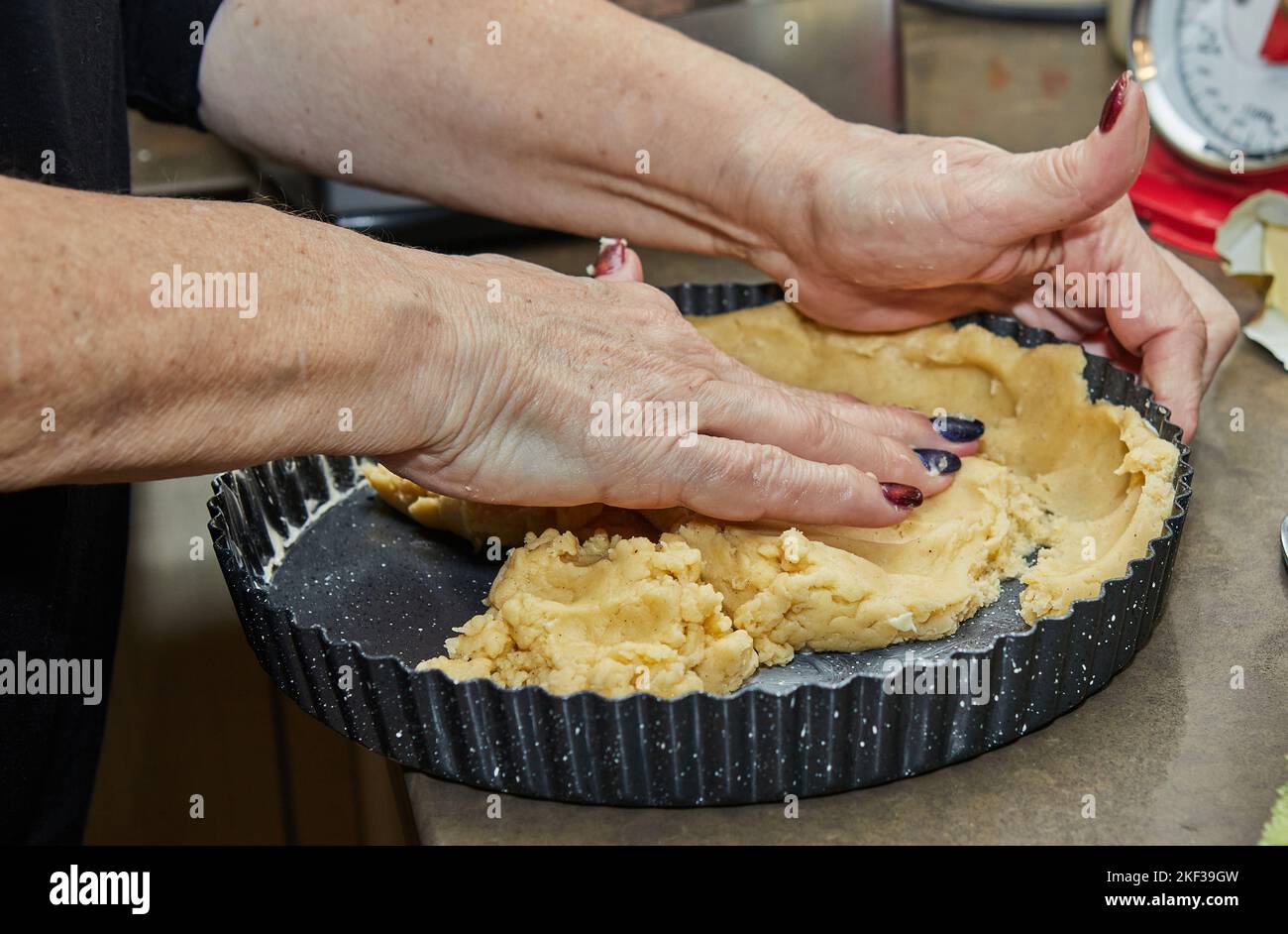 Cook kneads the dough in a mold for making a pie in the kitchen Stock ...
