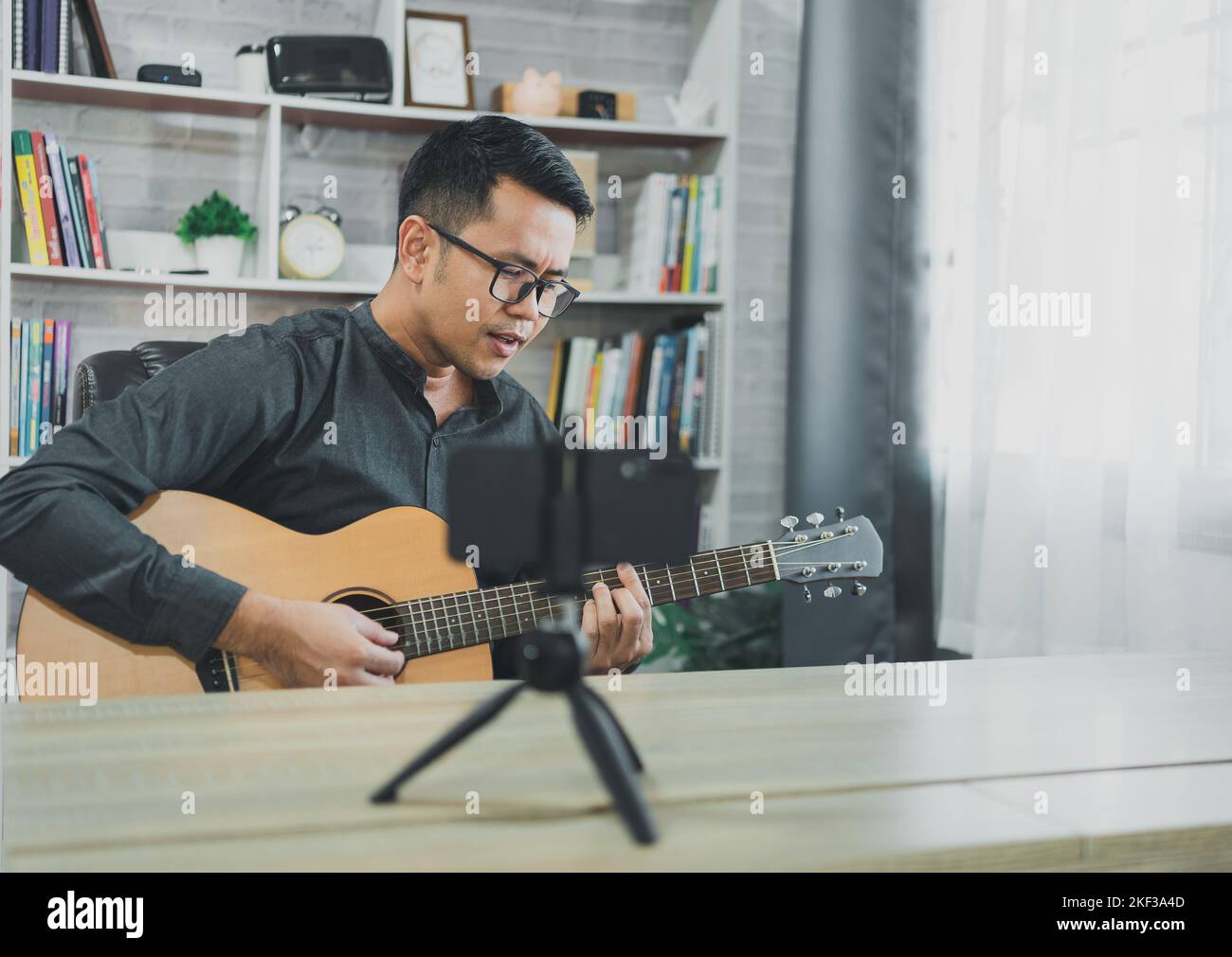 Asian music teacher man broadcasting live guitar lessons to students ...