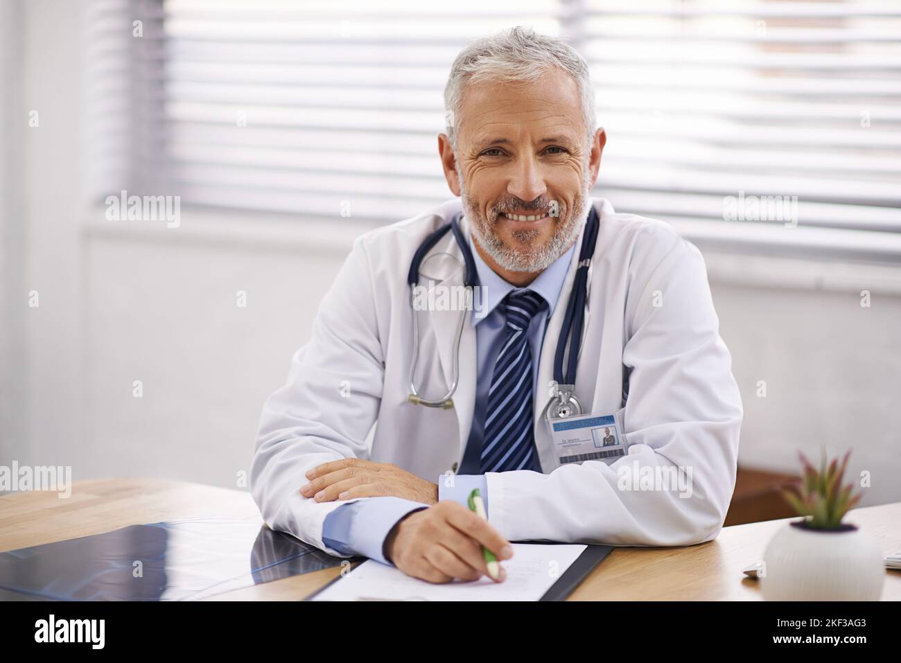 The doctor will see you now. Portrait of a mature male doctor sitting ...