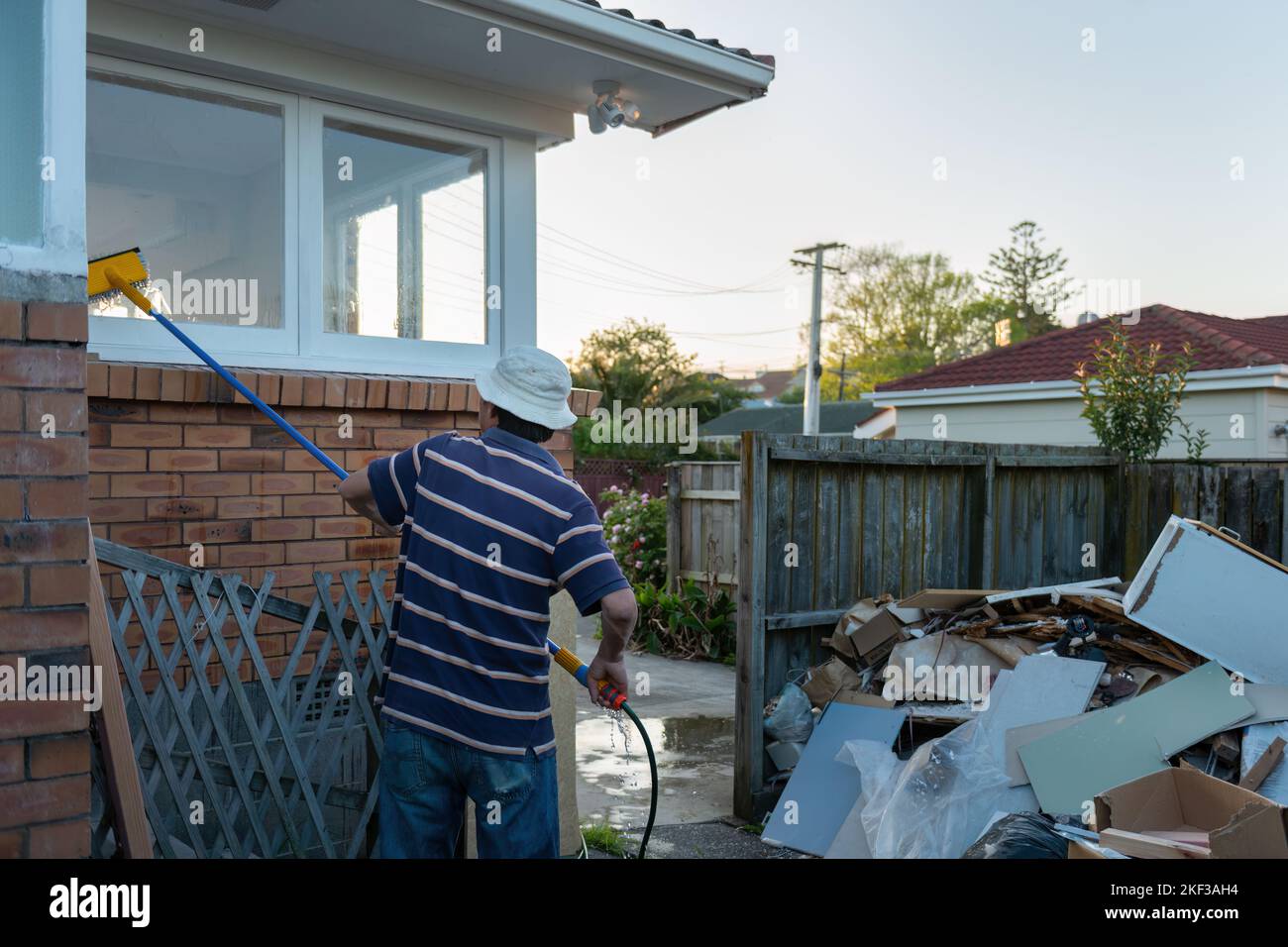 Man washing windows with long pole and brush. Construction rubbish from ...