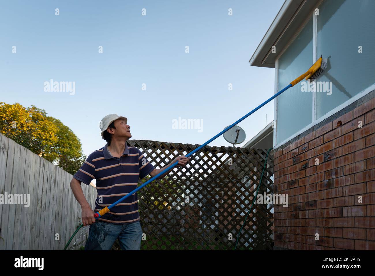 Man washing windows with long pole and brush. Home maintenance project ...