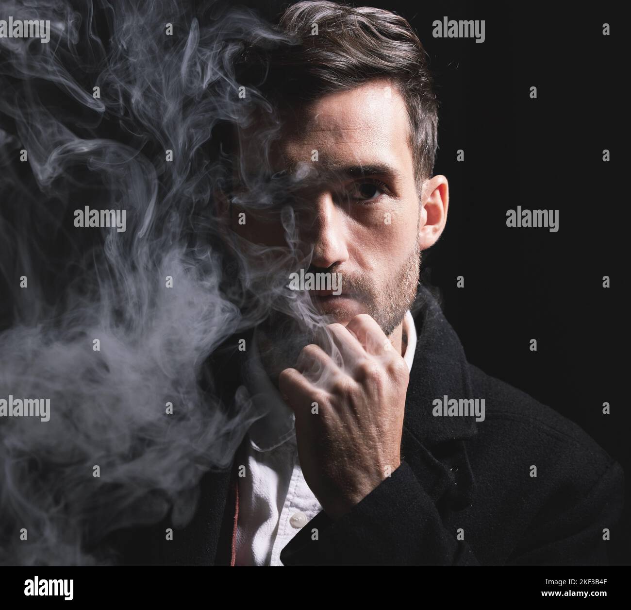 Face, fashion and smoke with a man portrait in studio on a dark ...