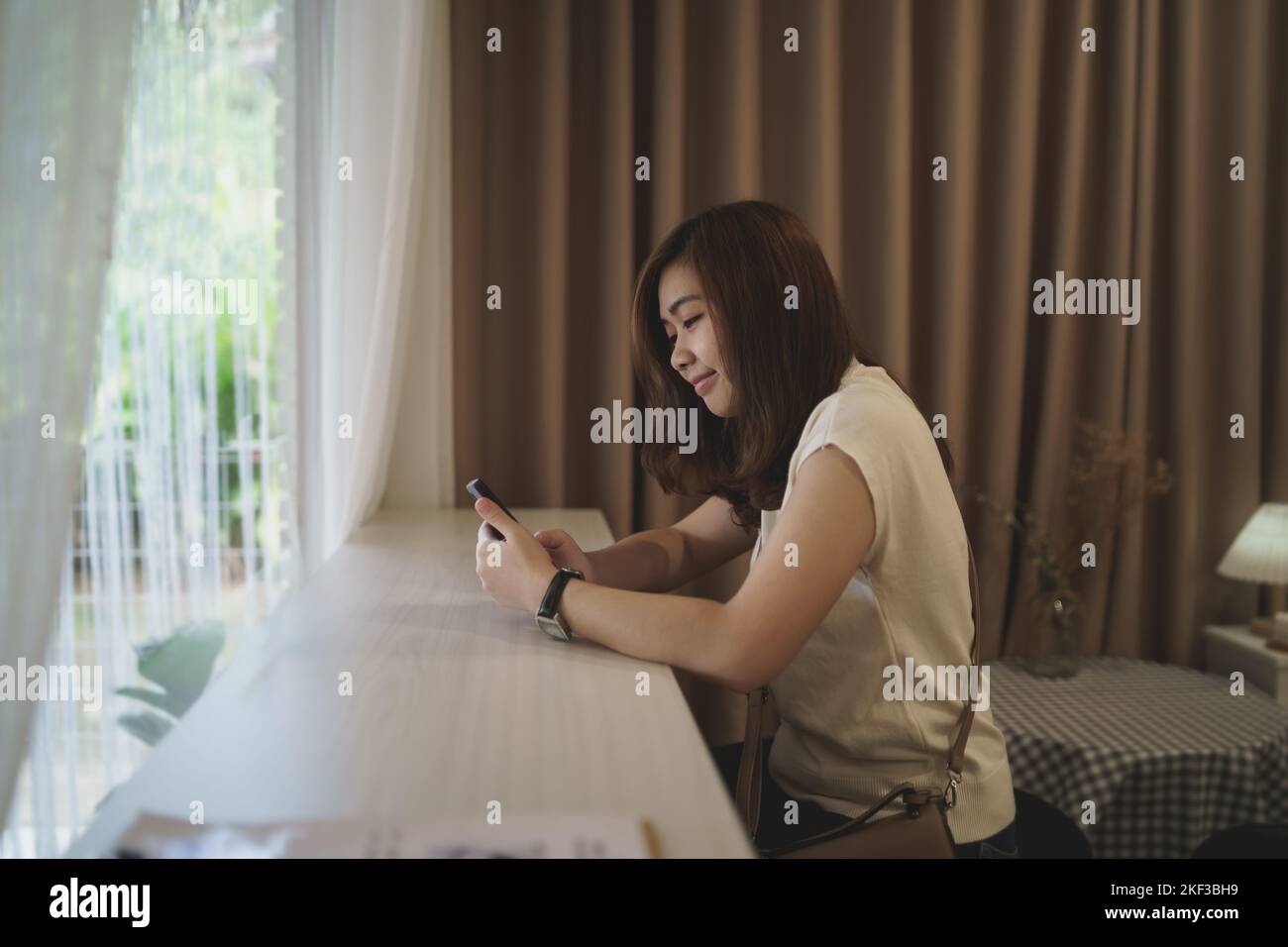 Young asian woman typing text message on smart phone in a cafe ...