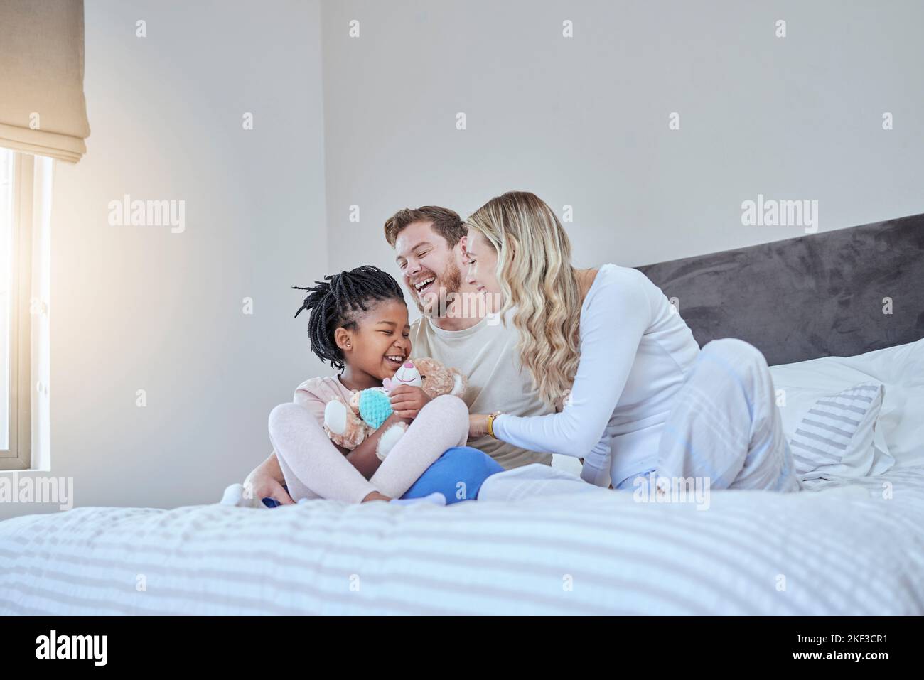 Interracial, adoption family and bed with smile, happiness and bonding ...