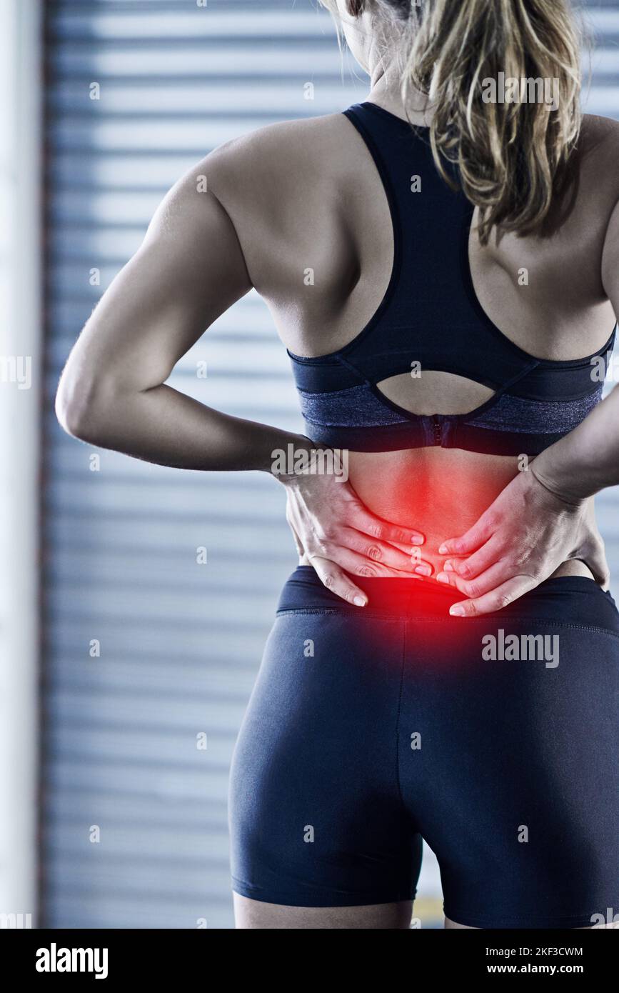 Want to get rid of back pain. Rearview shot of a young woman holding ...