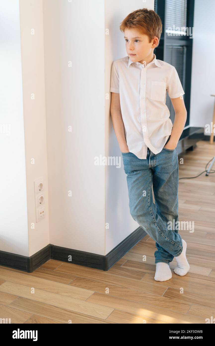 Vertical portrait of stylish child boy leaning against wall with hands ...