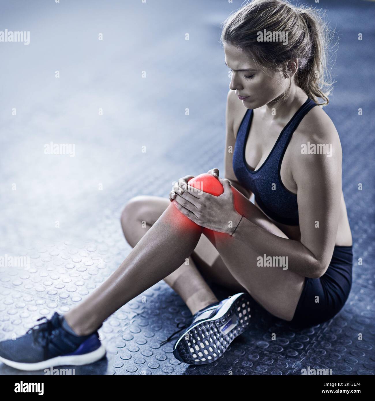 Let pain be your motivation. a young woman holding her injured knee ...