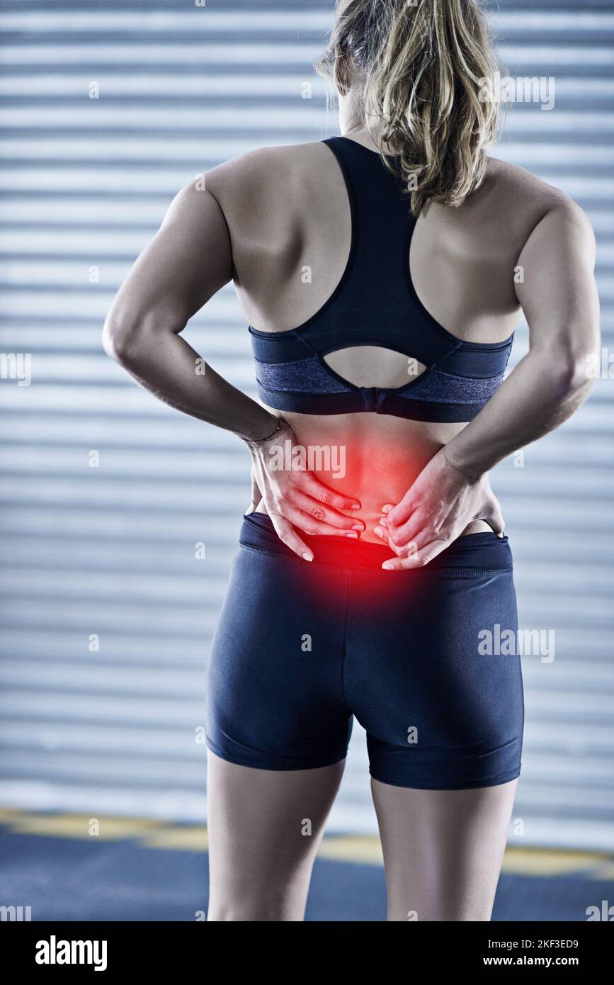 Dont let back pain get you down. Rearview shot of a young woman holding ...