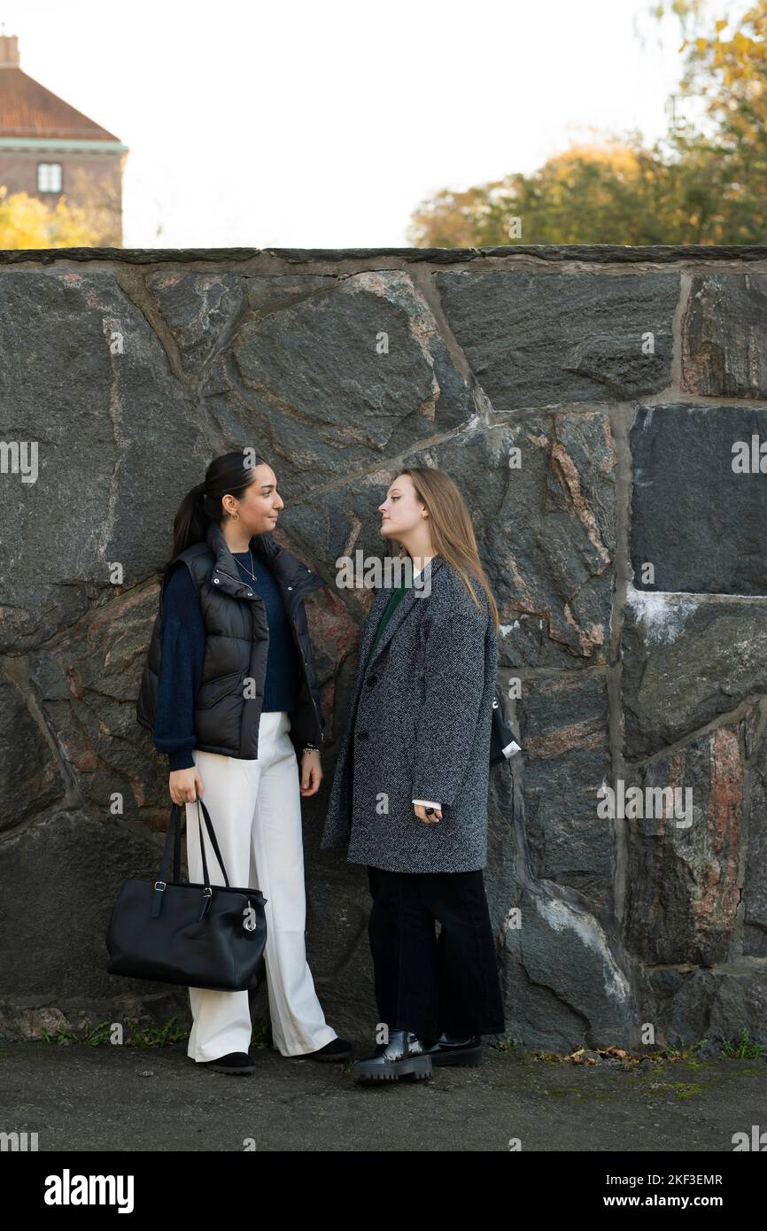 Young women talking by wall Stock Photo - Alamy