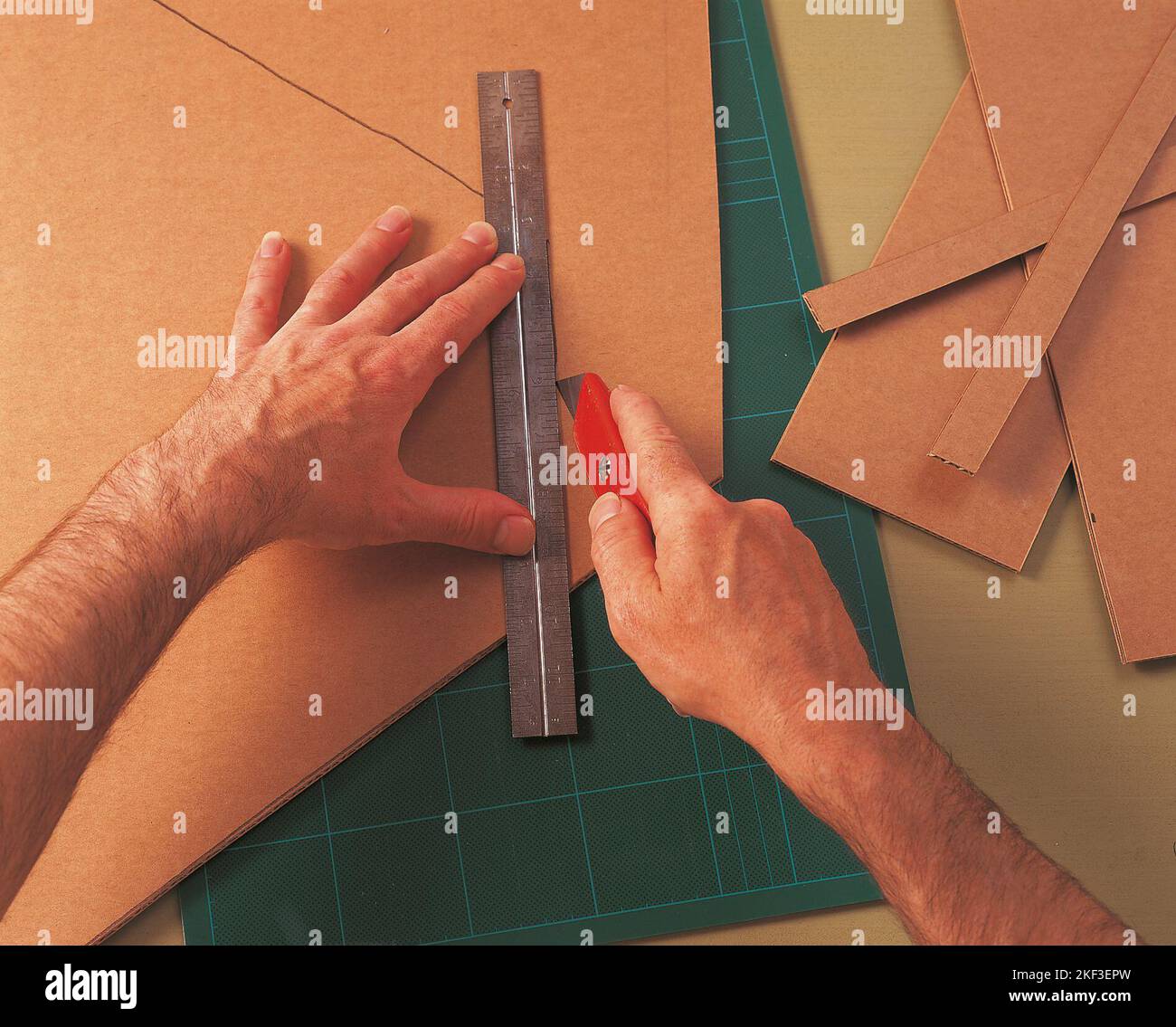 Cutting out corrugated cardboard with utility knife Stock Photo - Alamy