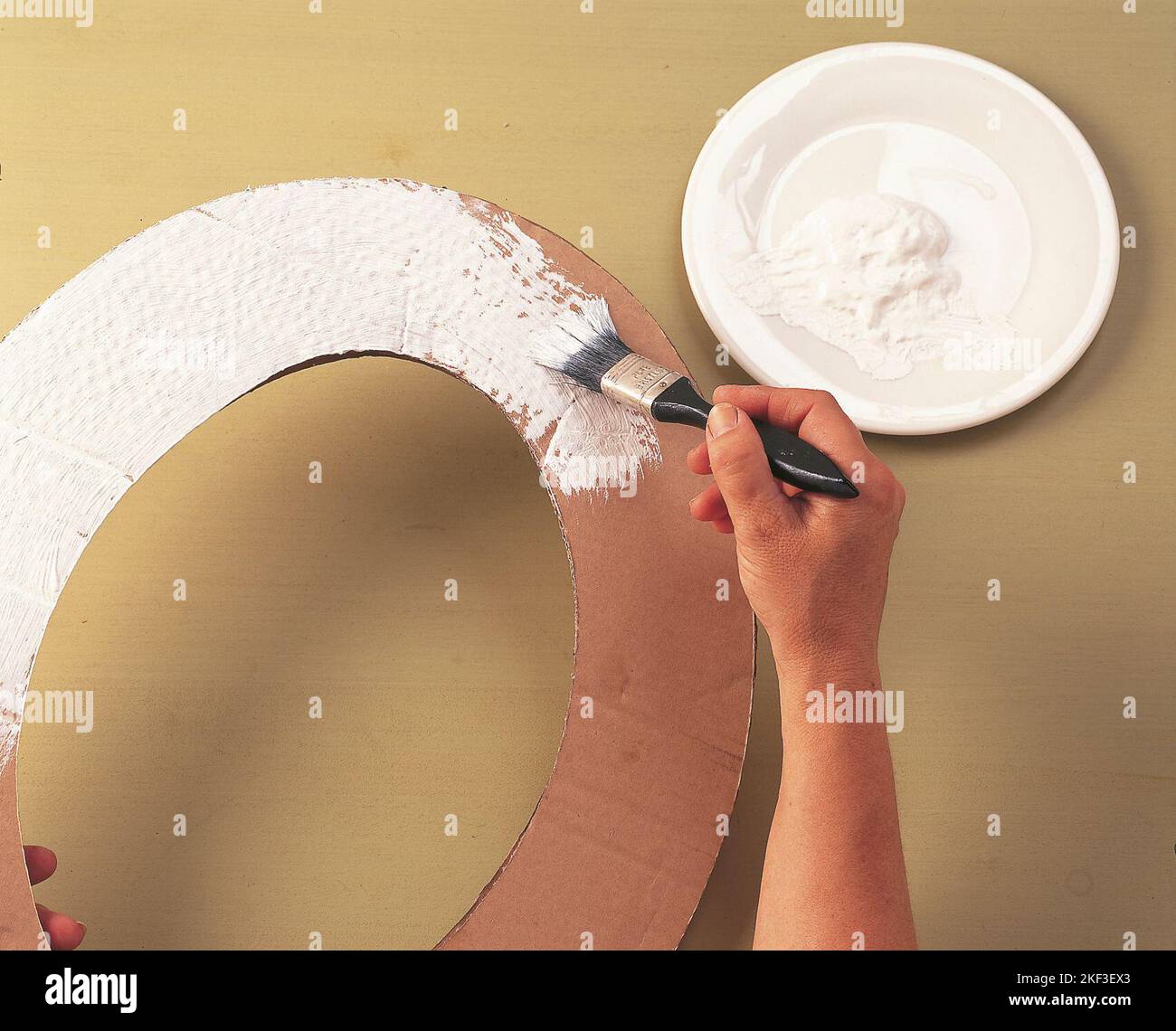 Painting the oval cardboard base Stock Photo - Alamy