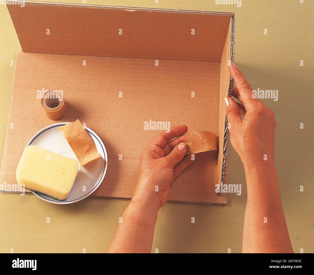 Folding and sticking the cut out cardboard shape Stock Photo - Alamy