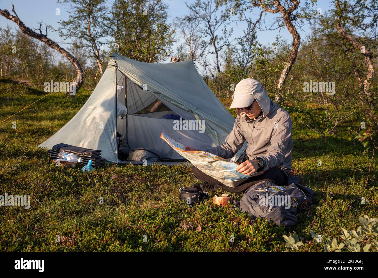 Man reading at map while camping Stock Photo - Alamy