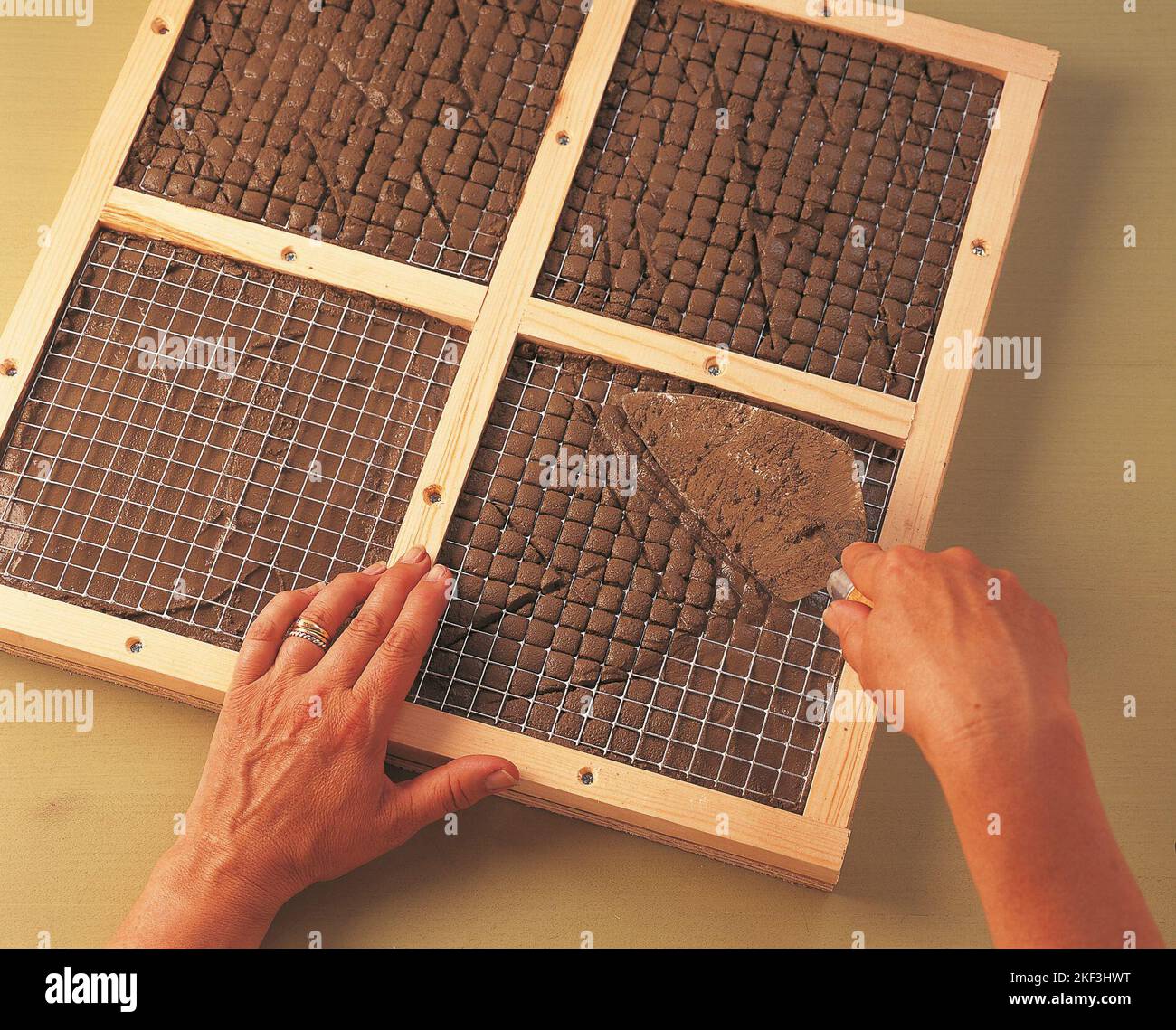 Pressing the mesh squares down into the cement Stock Photo - Alamy
