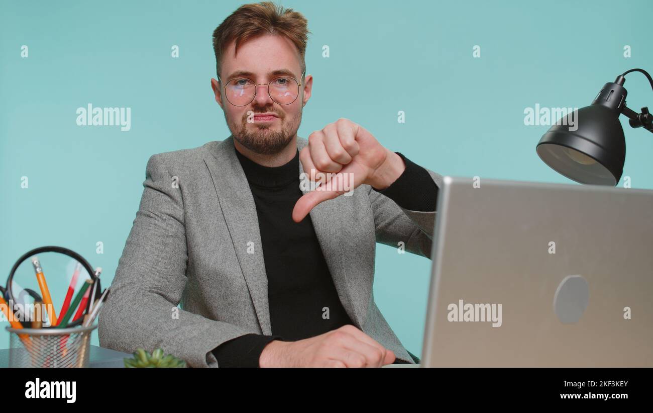 Dislike. Upset bearded business man sitting at office desk showing ...