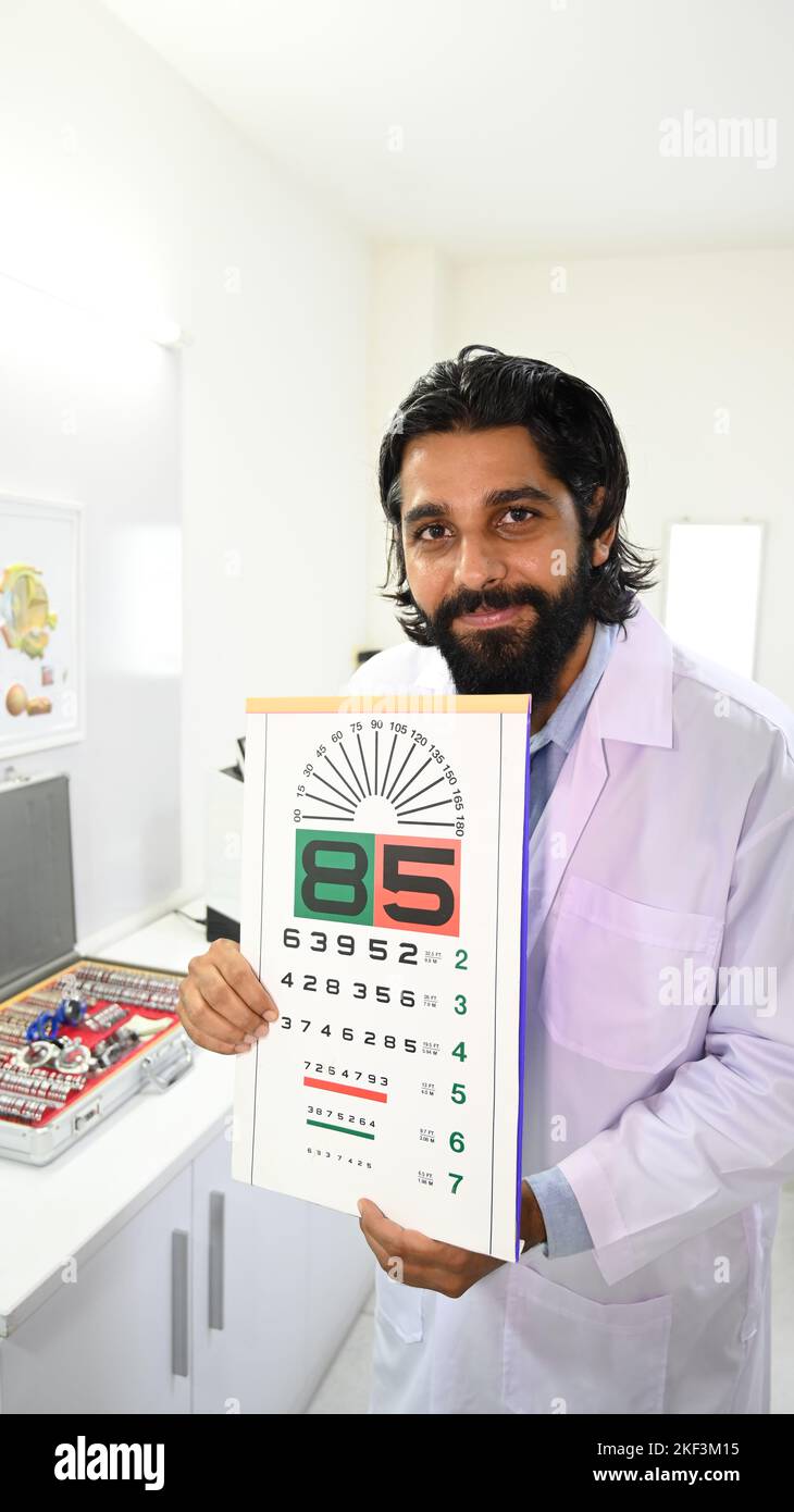 Portrait of Indian male ophthalmologist holding eyesight test chart ...