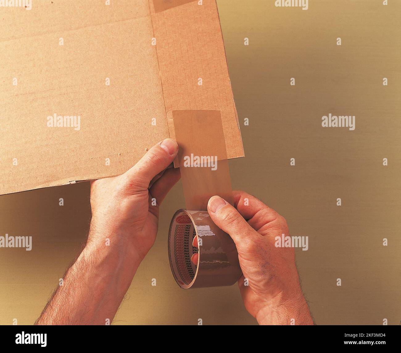 Attaching a cardboard strip with adhesive tape Stock Photo - Alamy
