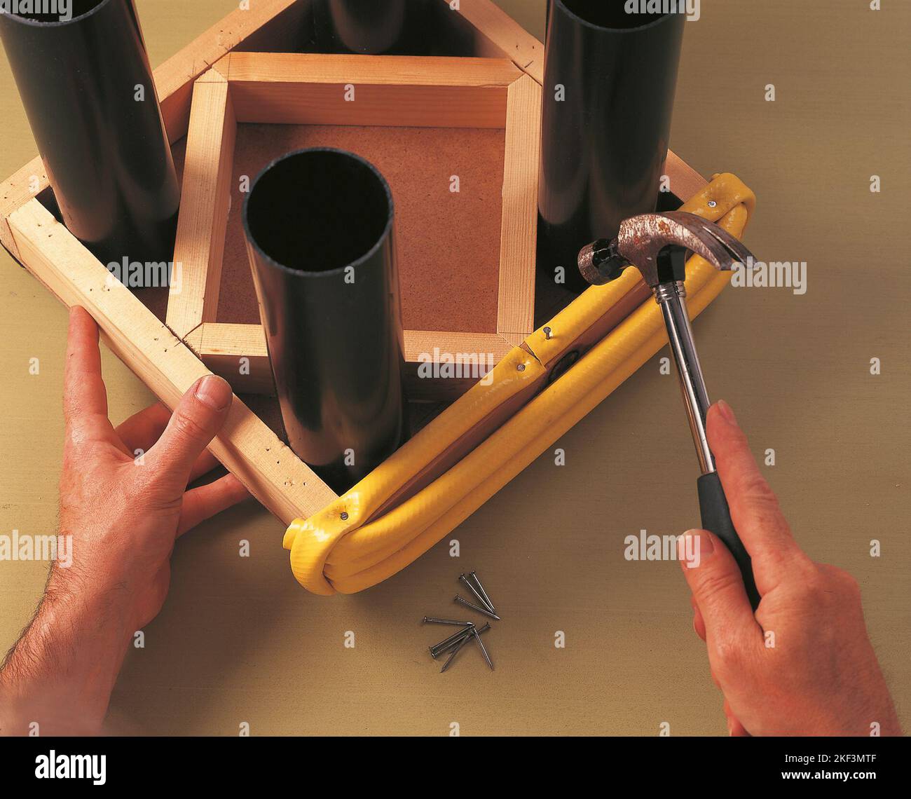 Nailing a hose piece to the underneath of the stool frame Stock Photo ...