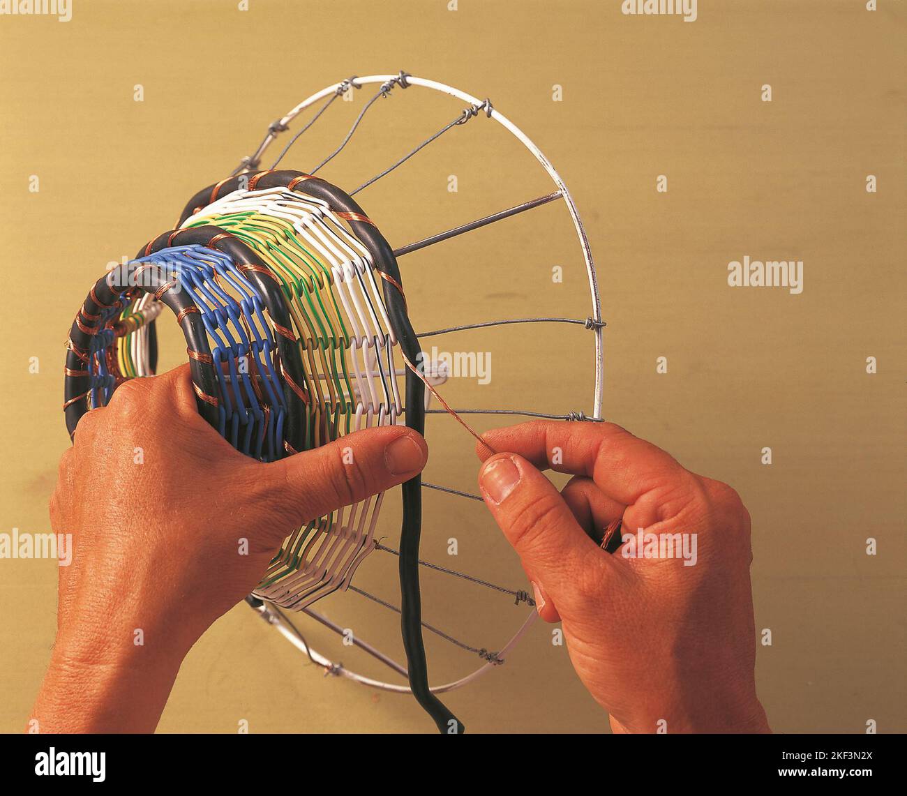 Securing a black cable to the lampshade frame with copper wire Stock ...