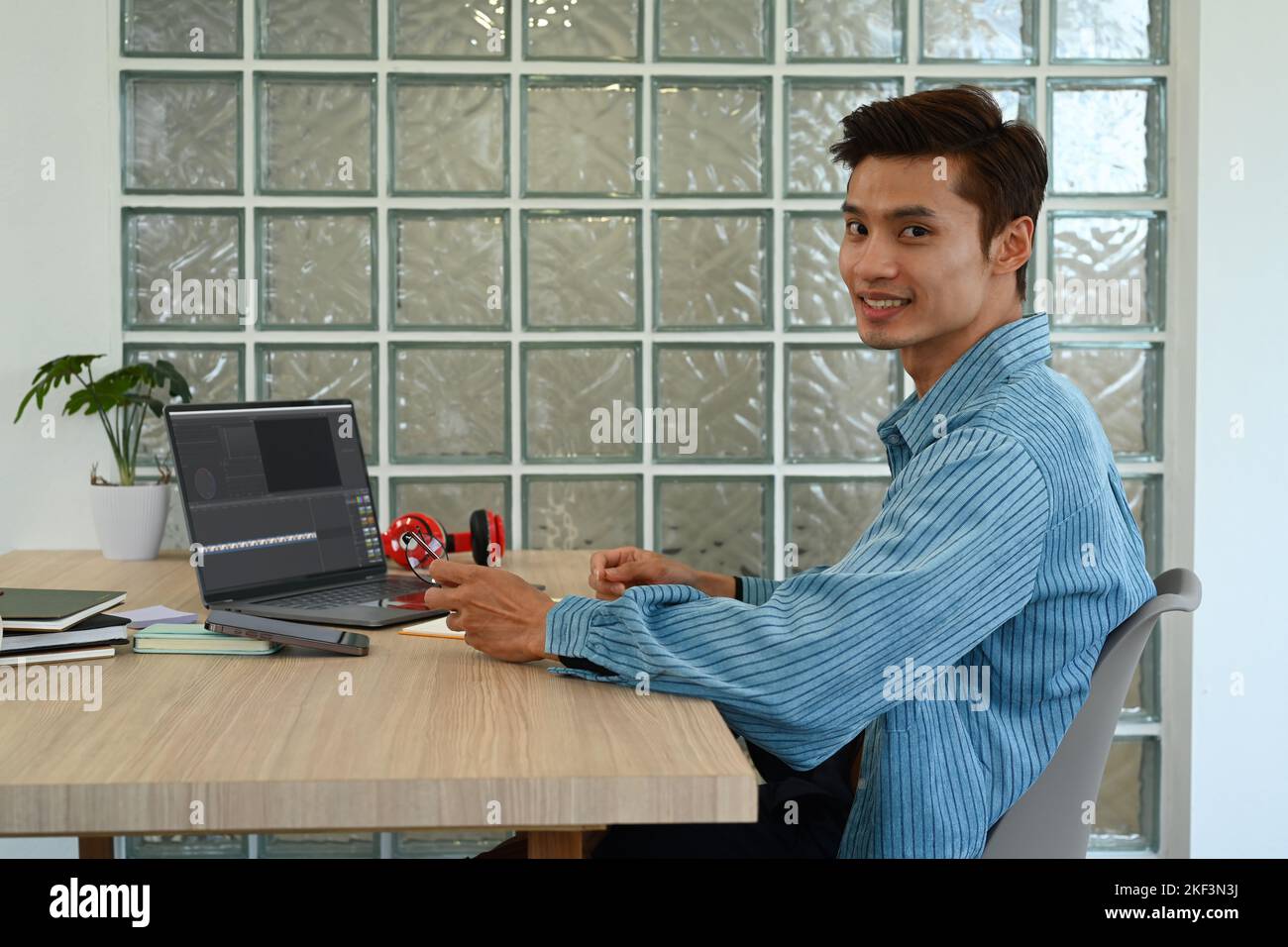 Asian male video editor working with footage and sound on laptop at ...