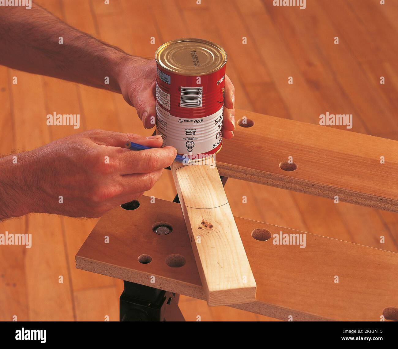 Drawing the circumference of an olive can on a piece of wood Stock ...