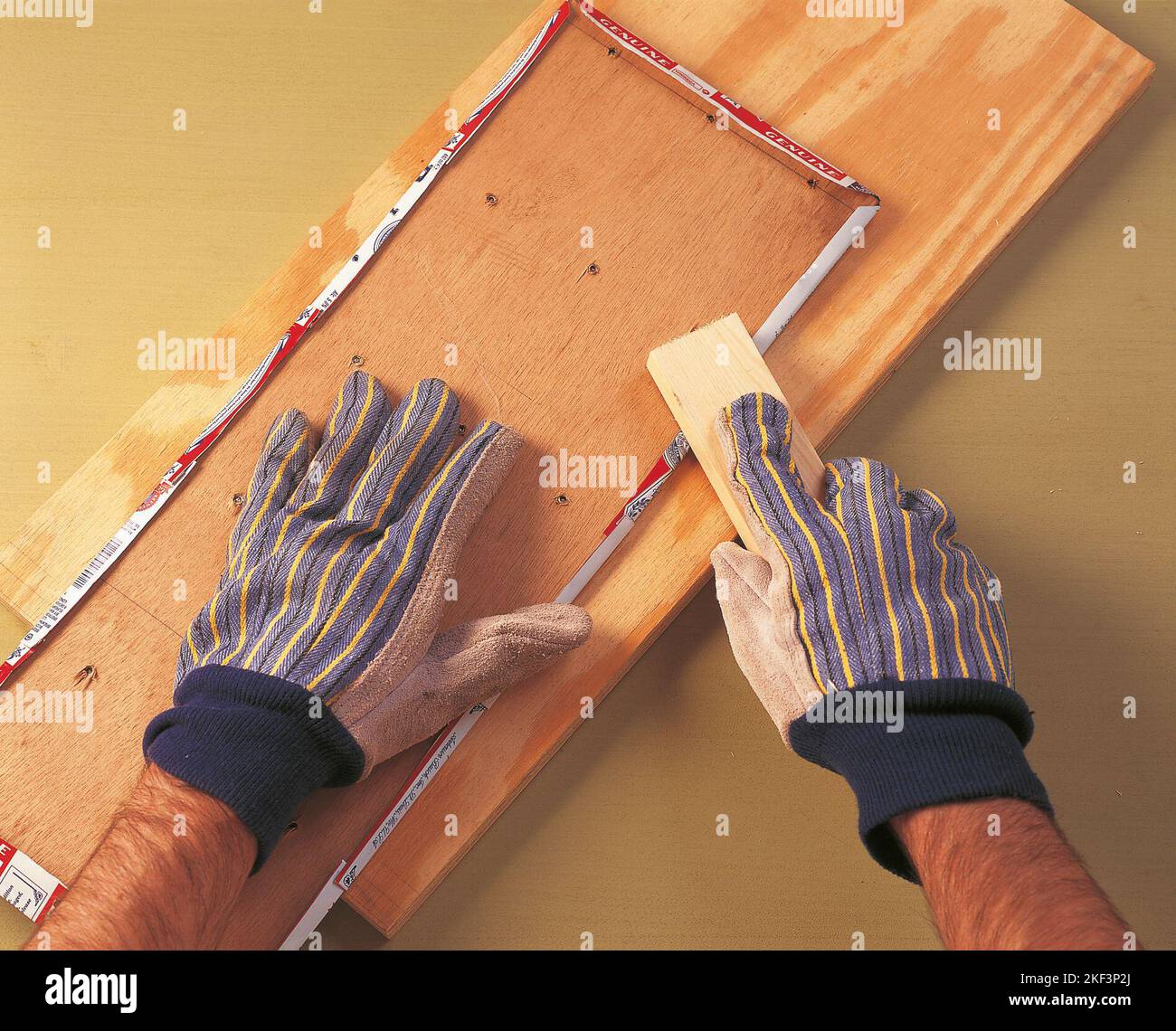 Holding a piece of scrap timber along a line of folded metal Stock ...