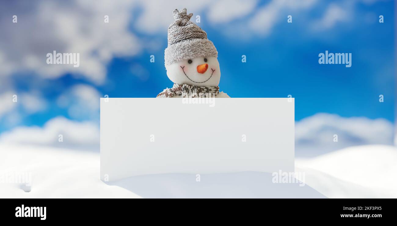 Snowman and a white empty card on snow, blue sky and winter snowy ...