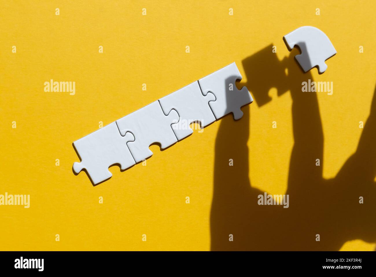 Shadow of hand with the piece of jigsaw puzzle to complete the line ...