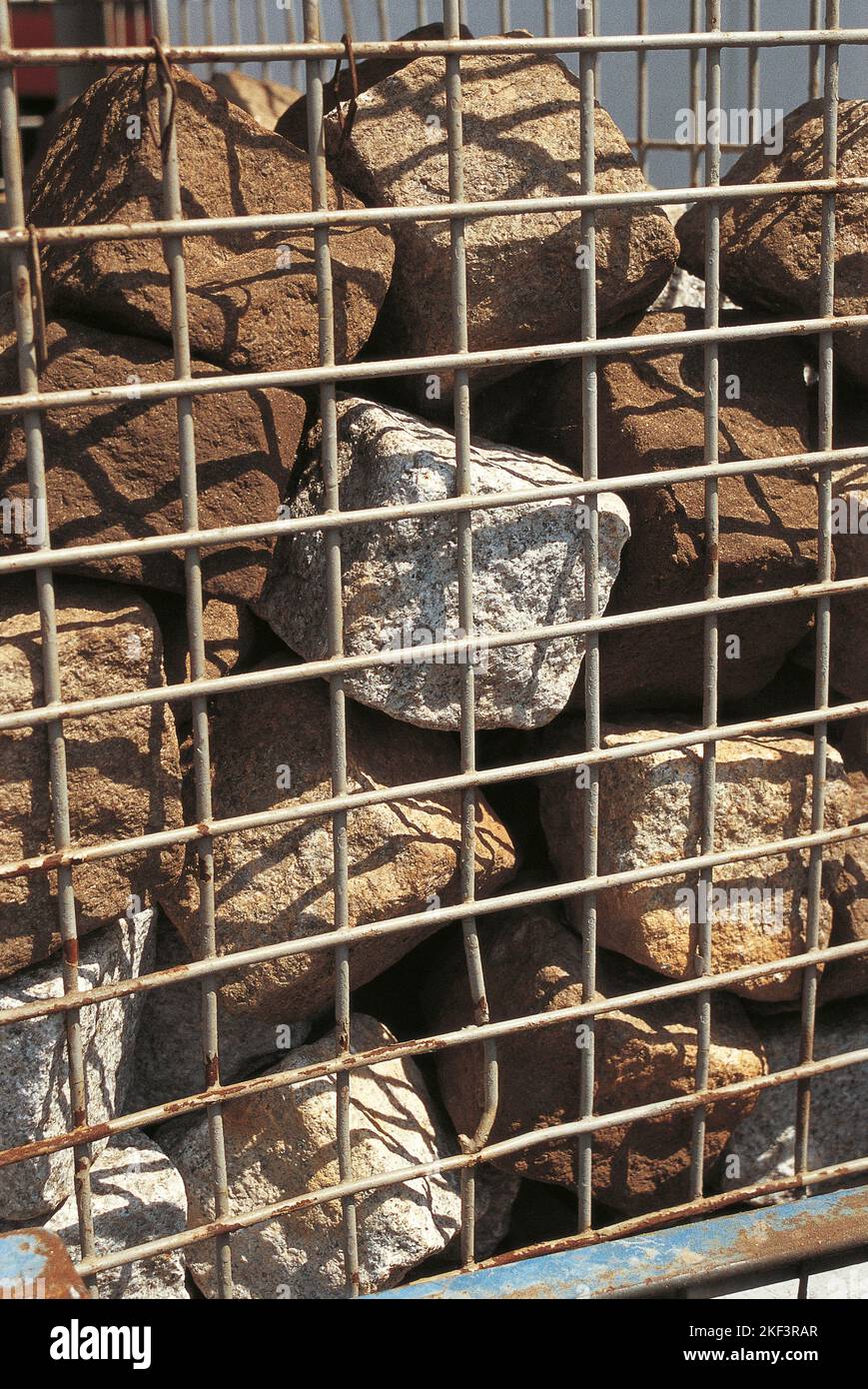 A heap of cobble stones in behind metal bars Stock Photo - Alamy