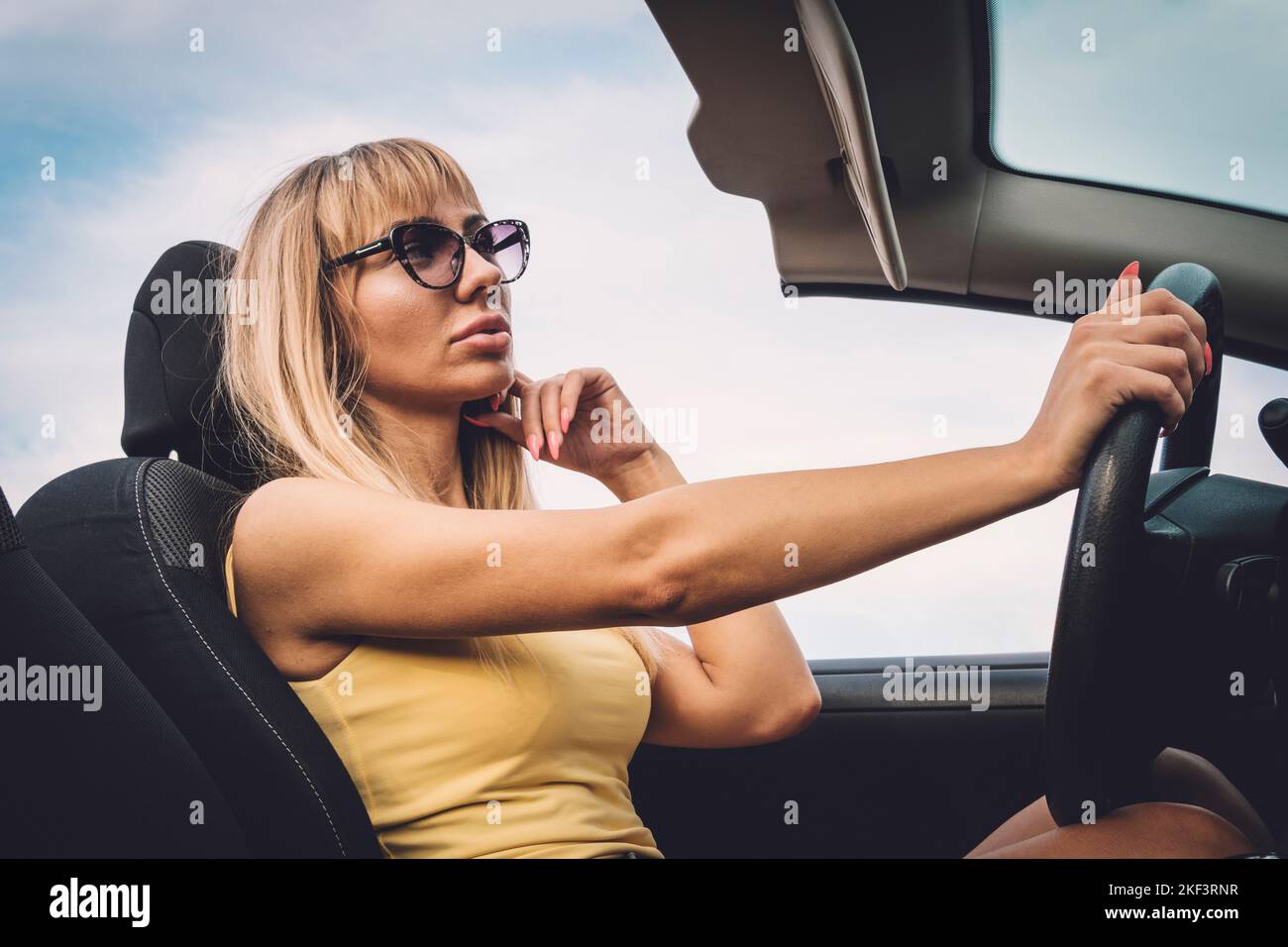 Young cute girl preens while driving. blonde admires herself in the ...