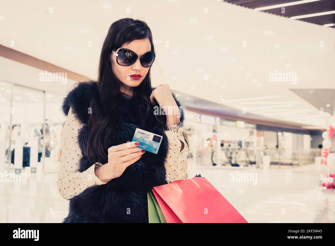 Woman in sun glasses after using credit card for shopping in the mall ...