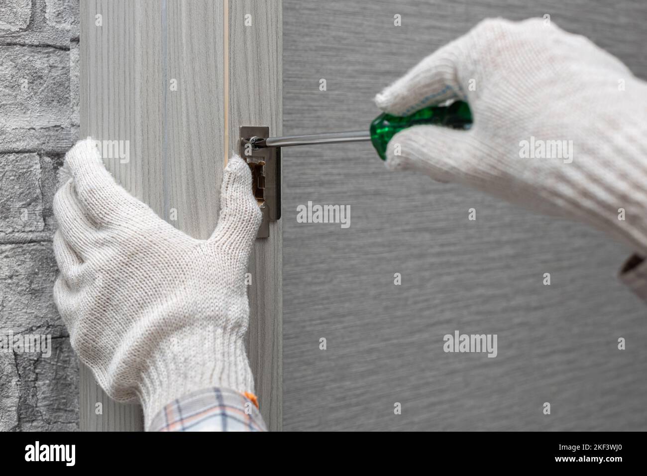 the master installs the door lock with a screwdriver. man fixing a door ...