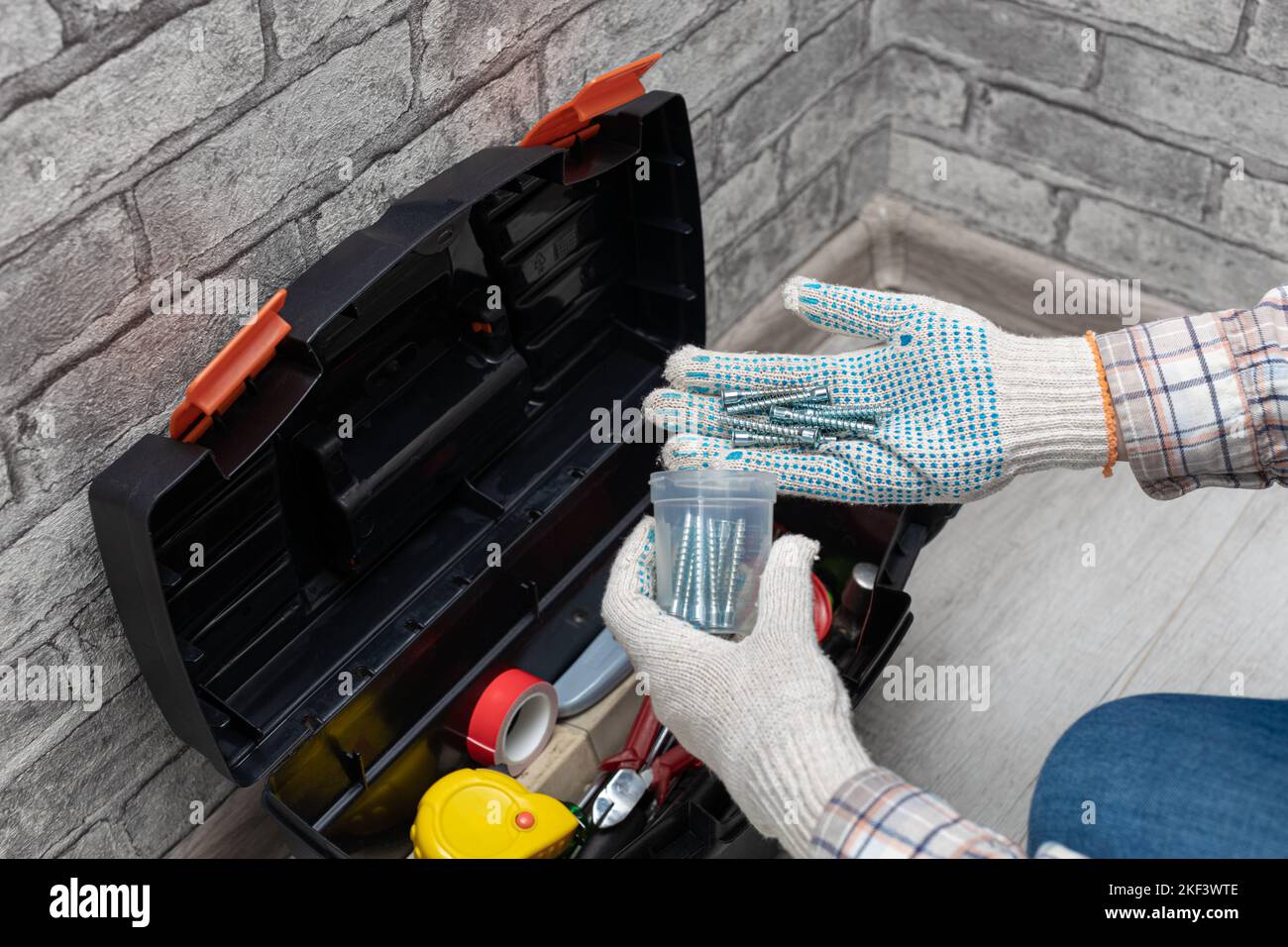 master holds a self-tapping screw in his hand. self-tapping screws on ...