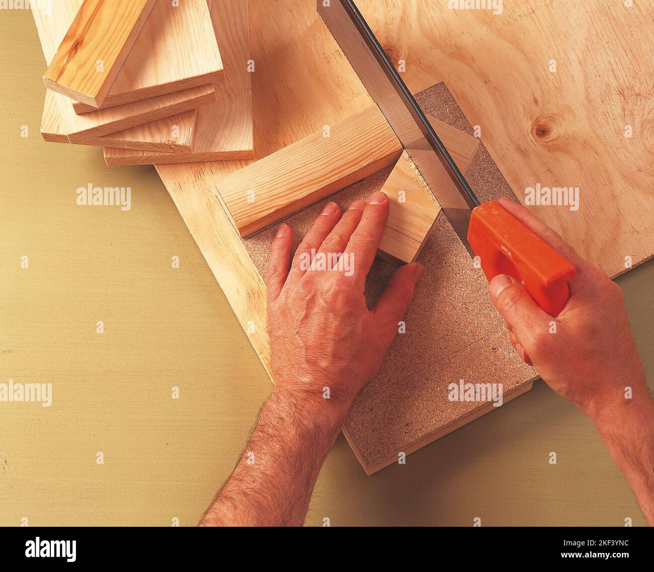 Cutting a piece of scrap timber with a handsaw Stock Photo - Alamy