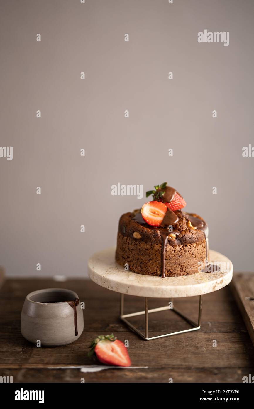 A vertical shot of a dripping chocolate cake with strawberries on a ...