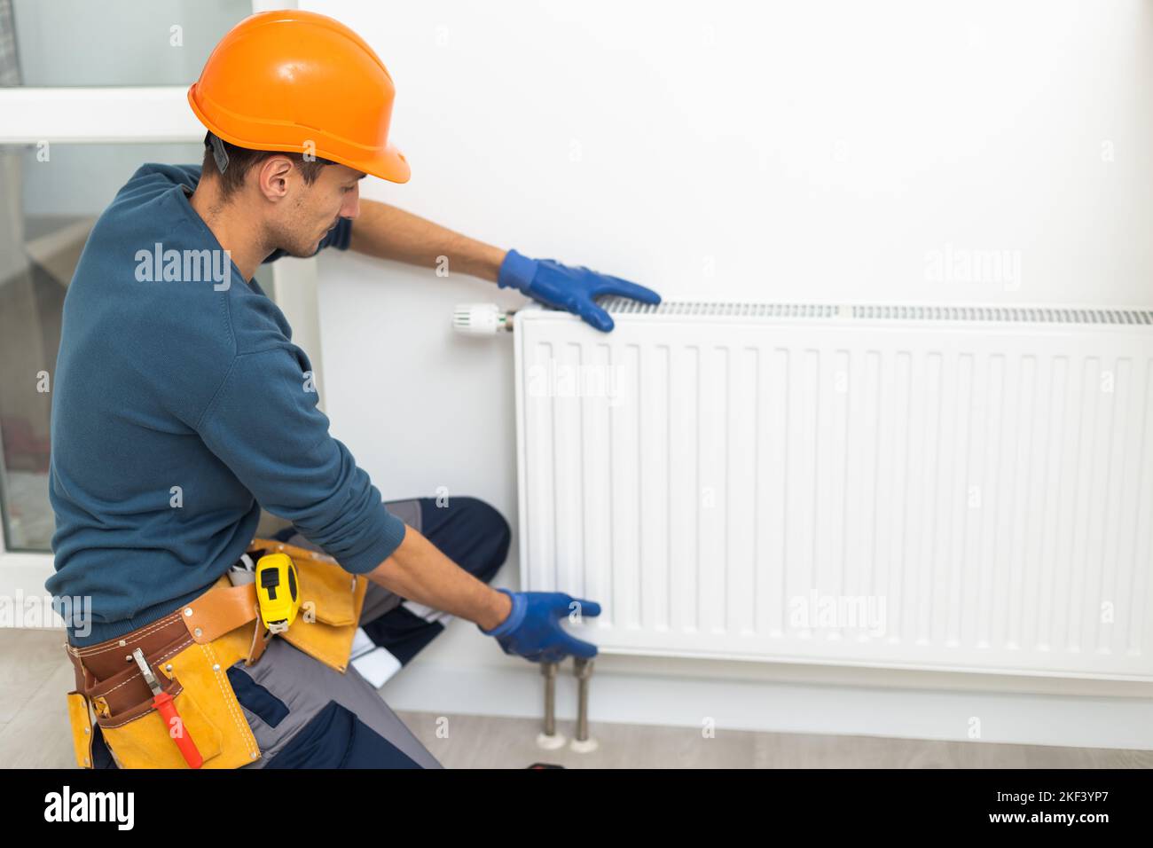 plumber at work. Installing water heating radiator Stock Photo - Alamy