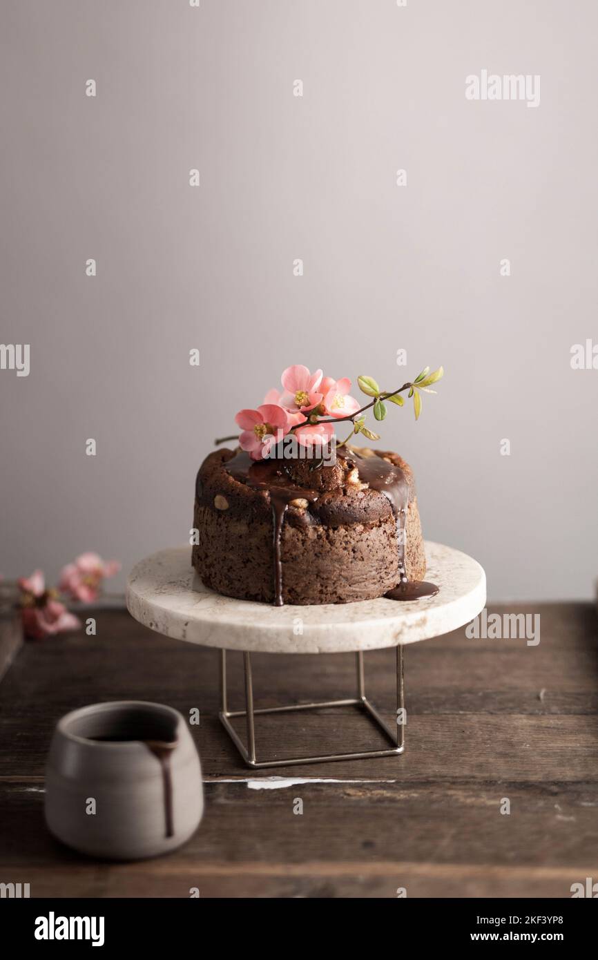 A vertical shot of a dripping chocolate cake with gentle pink flowers ...