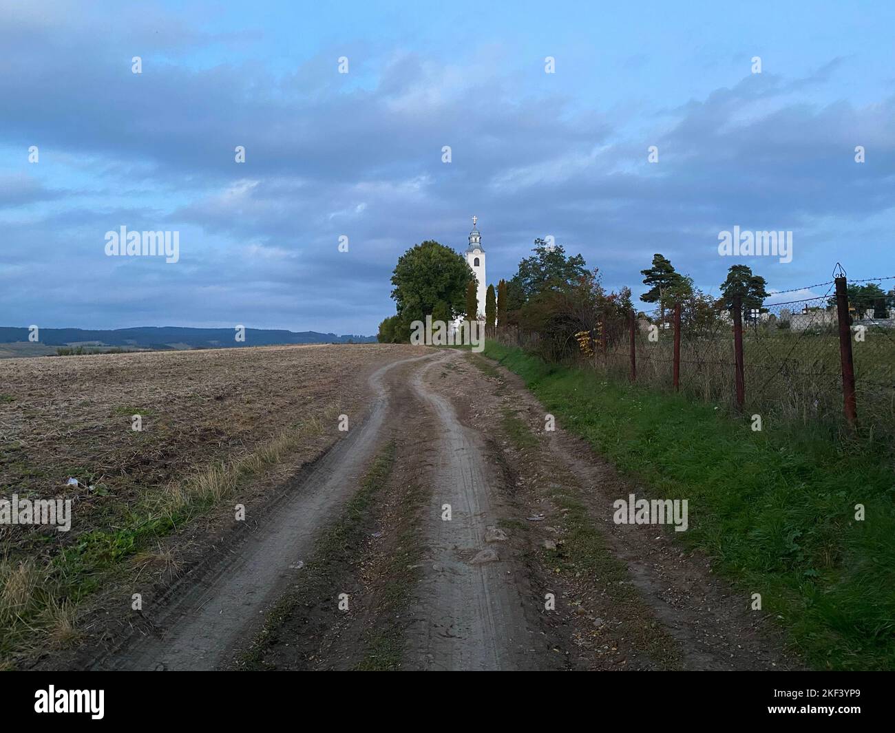 A pathway leading to a white church building in the distance in a field ...