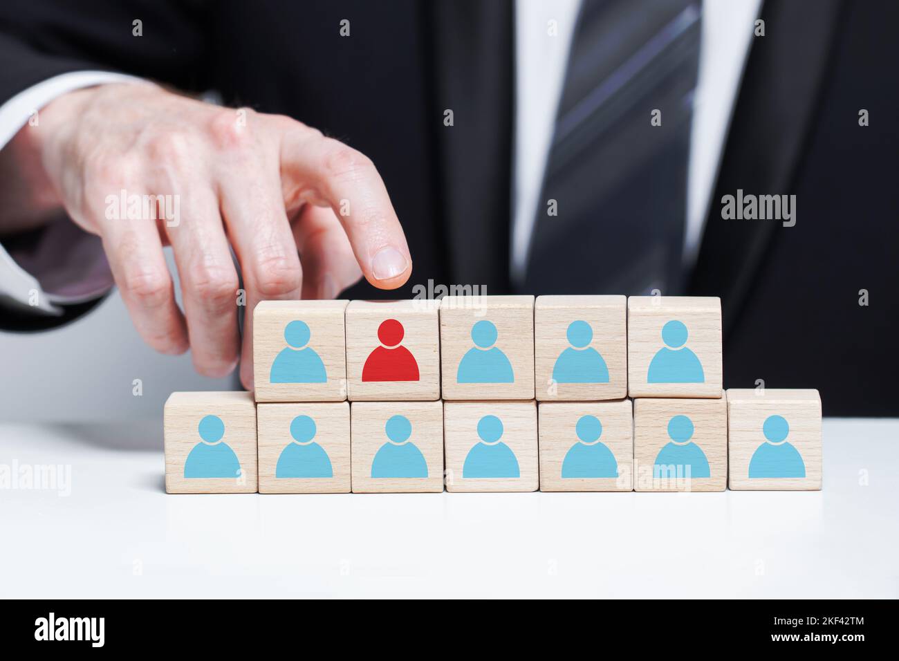 Wooden blocks with blue and red people icons and businessman hands ...