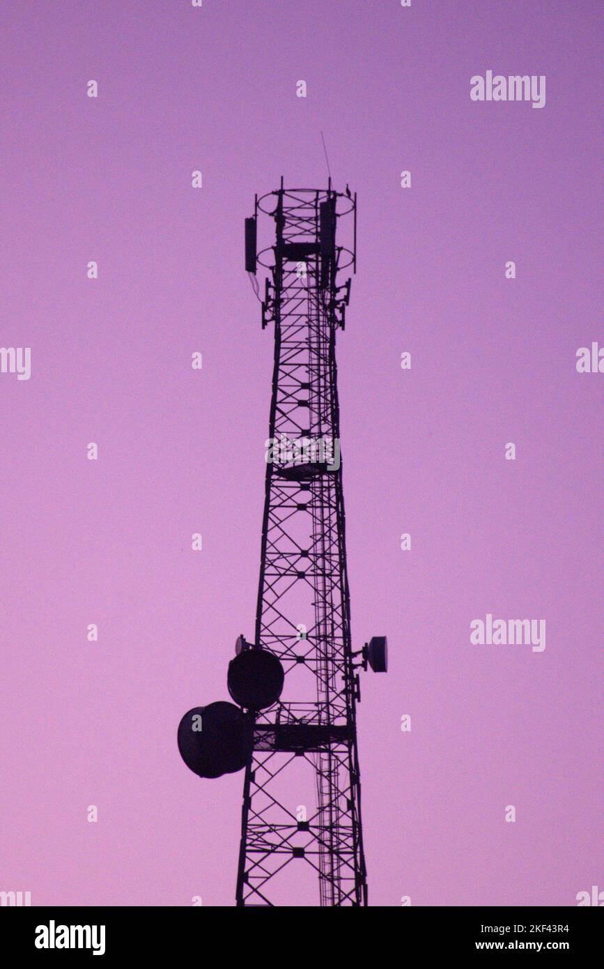 A vertical shot of a telecommunications tower against the purple sky ...