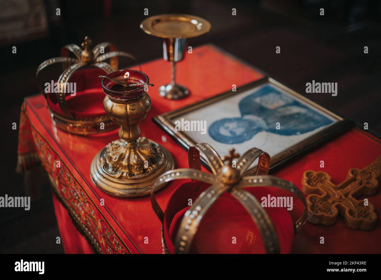 The golden crowns, cross, and an icon laying on a red church table ...