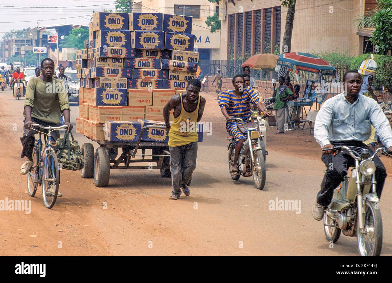 Burkina Faso, Ouagadougou. A man is transporting a cargo of Omo washing ...