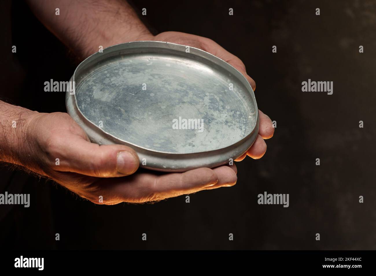 Male hands holding empty plate on dark background, lack of food, hunger ...